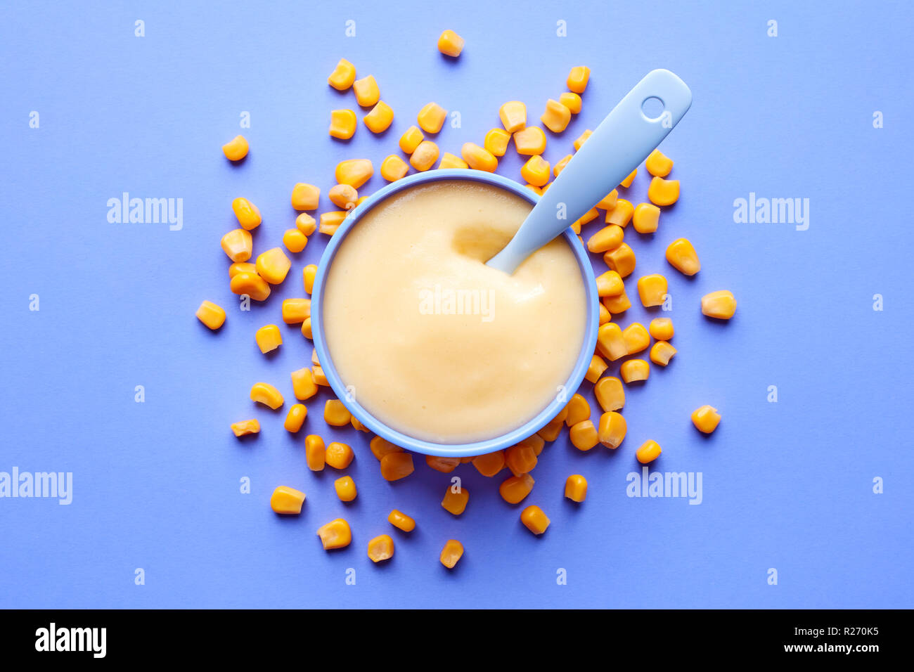 Light blue bowl of corn porridge for babies on blue background, top ...