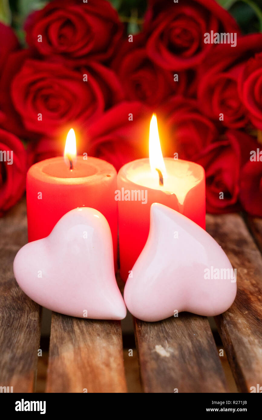 Two burning candles with fresh roses Stock Photo - Alamy