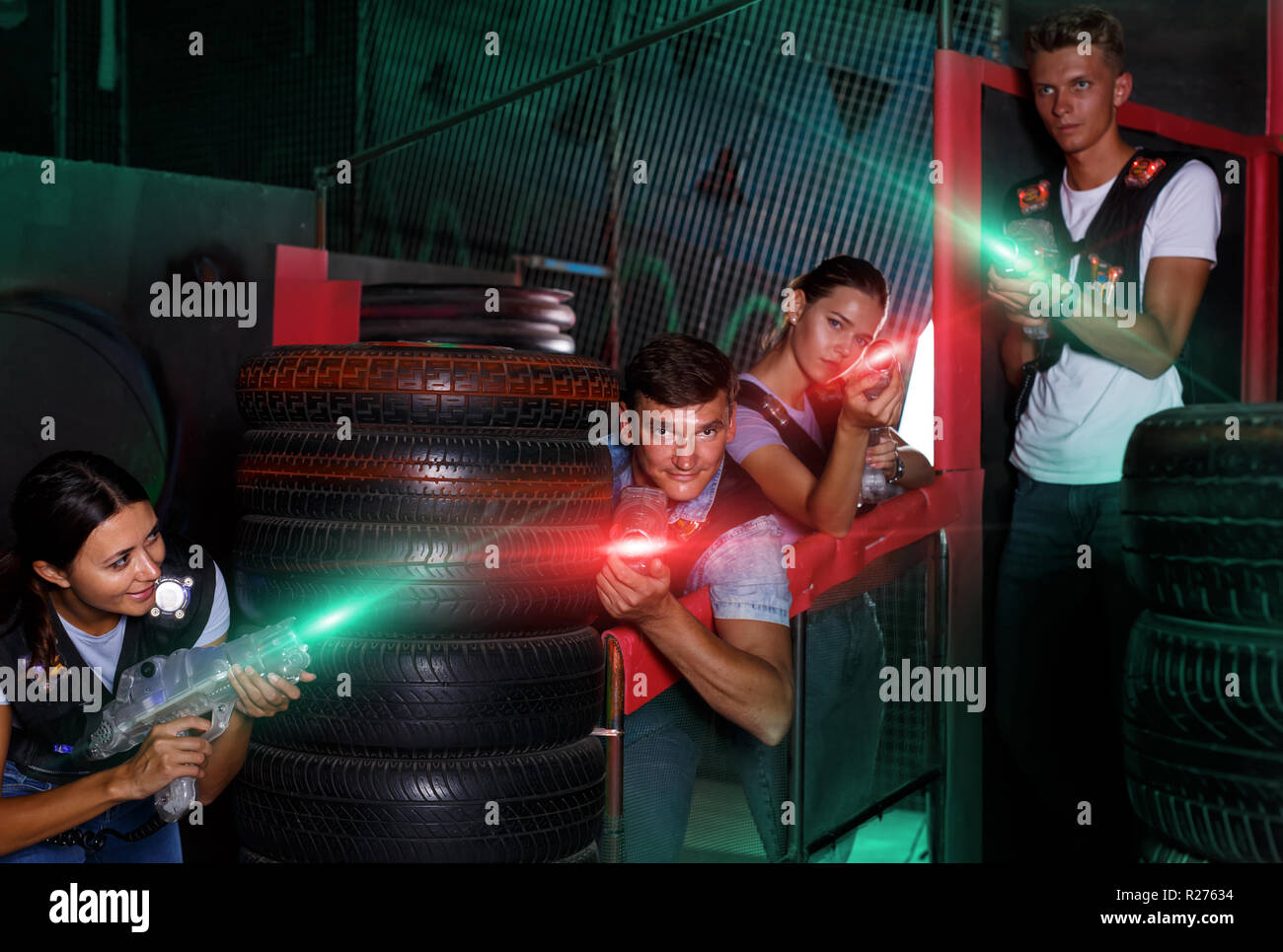 Group of young friends playing laser tag game with laser guns near ...
