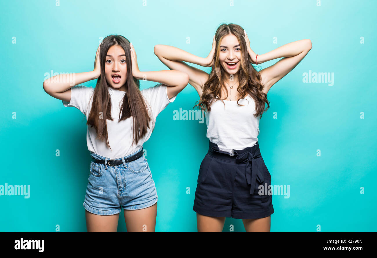 Portrait of two funny women covering ears isolated over green ...