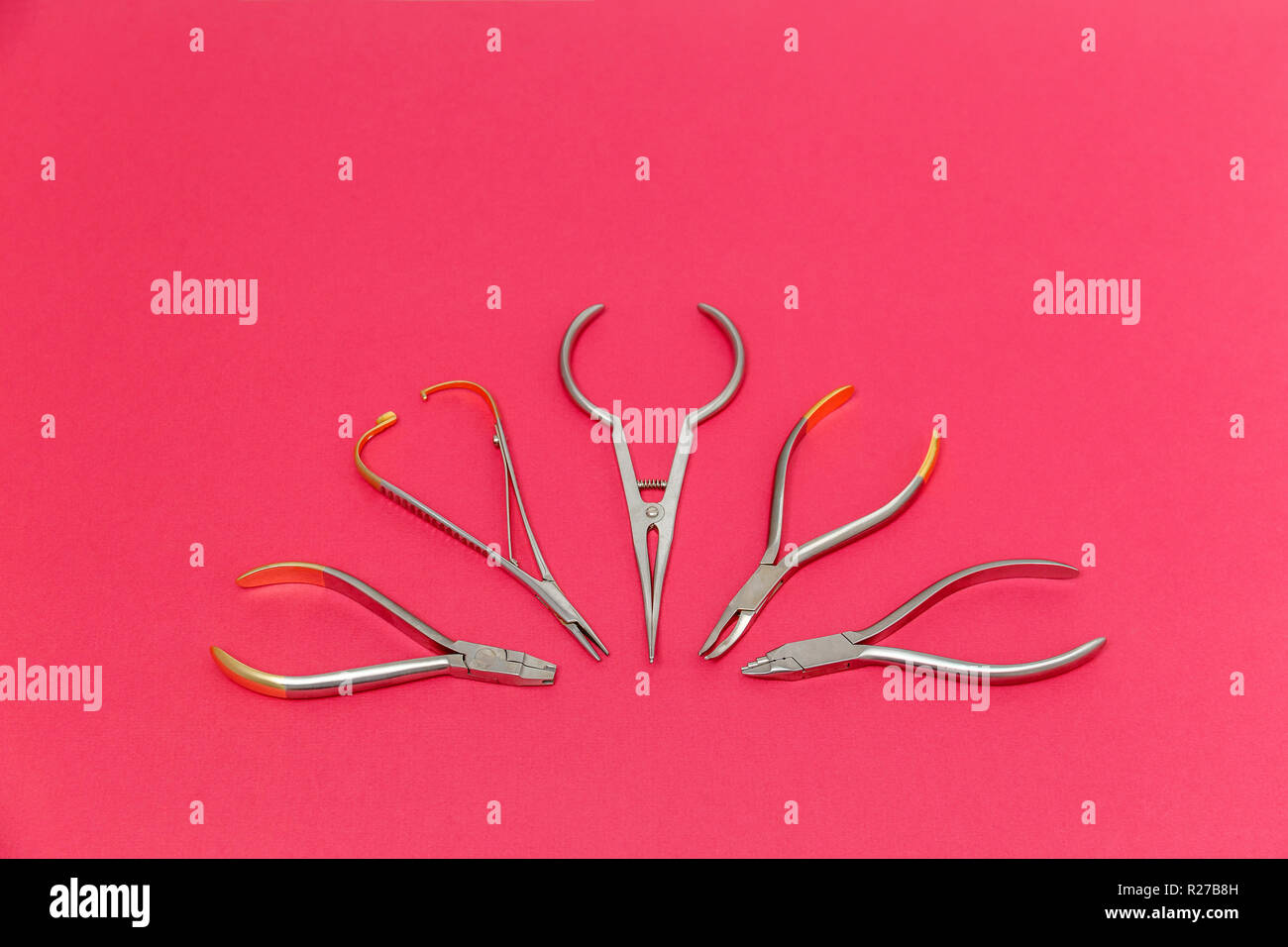 Orthodontic set of medical metal tools on pink background, closeup ...