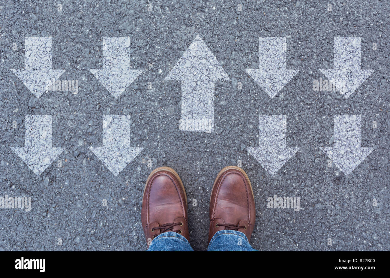 Top view of man wearing shoes choosing a way marked with arrows ...