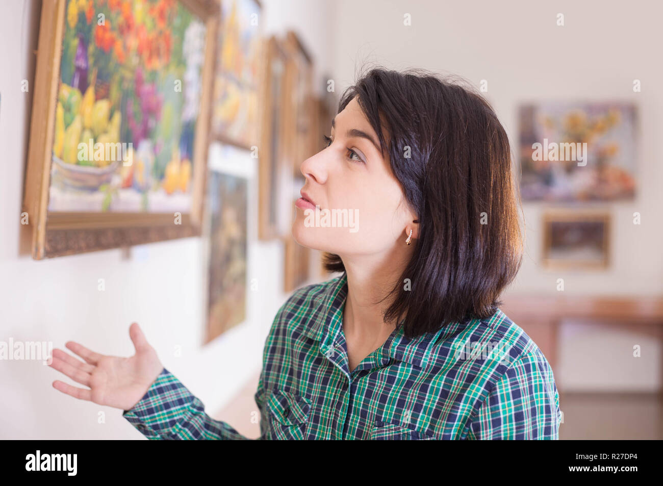 Young woman looking at painting in art gallery Stock Photo - Alamy