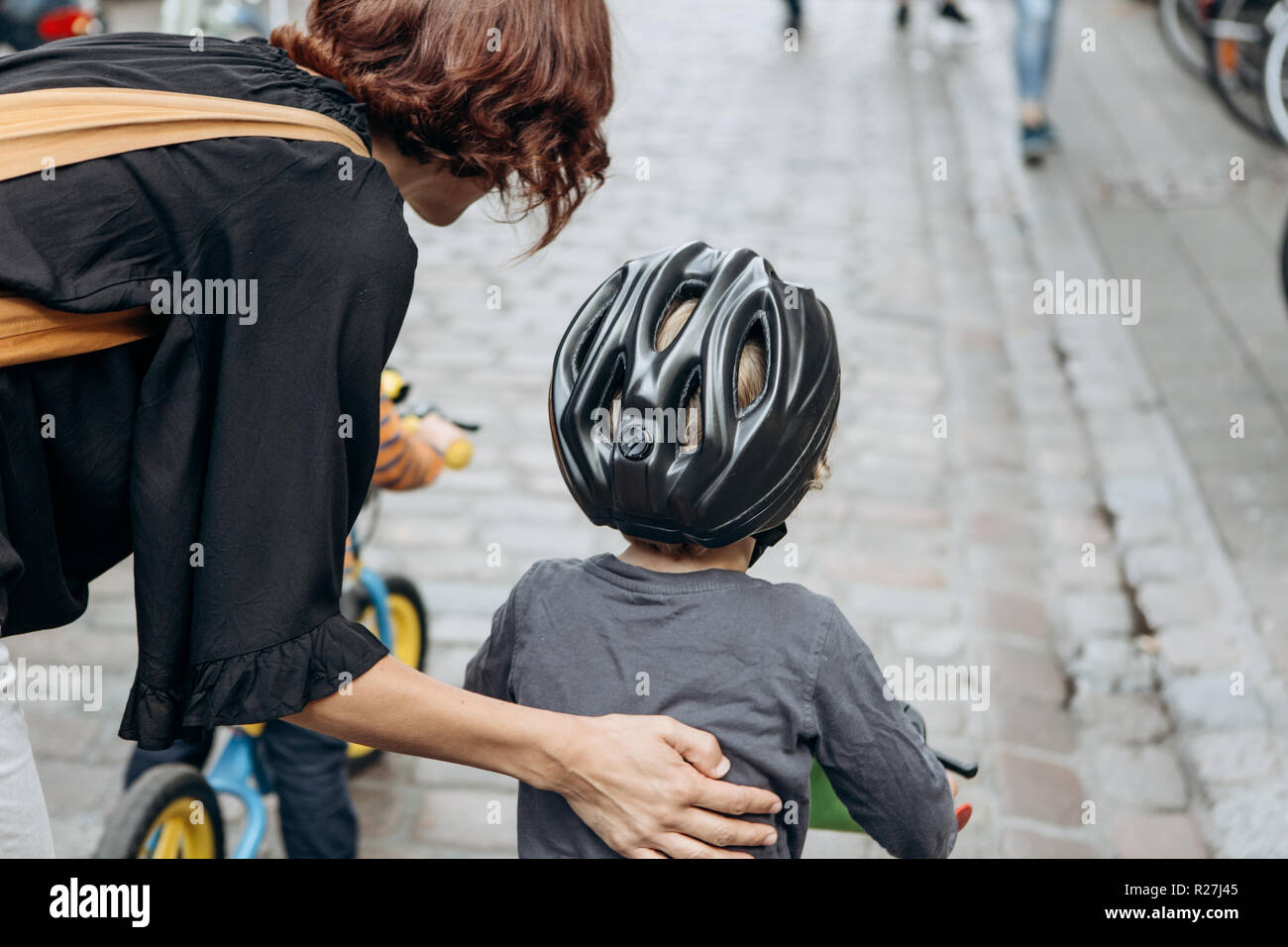 Mother teaches a child to ride a bike on a city street. Joint pastime ...
