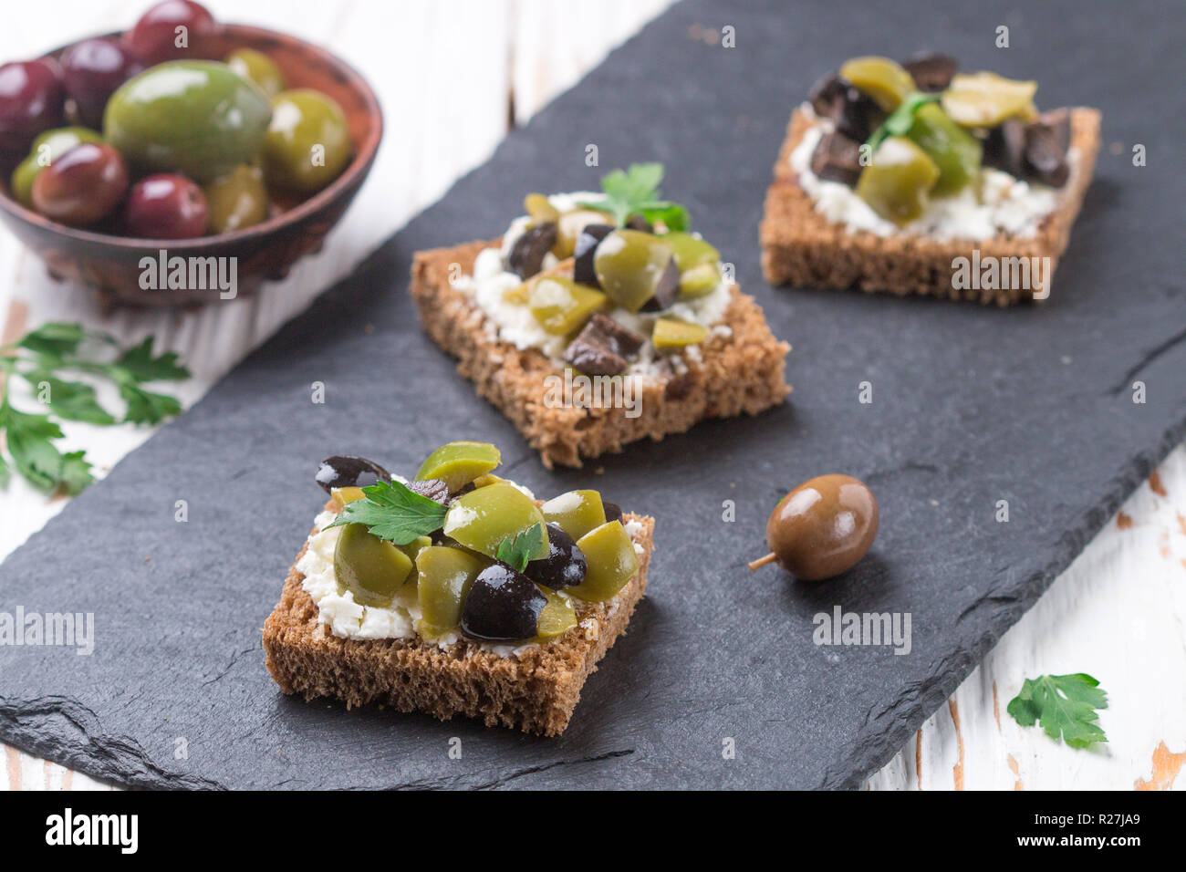Rye bread toast (canape) with black and green olives, feta cheese and ...