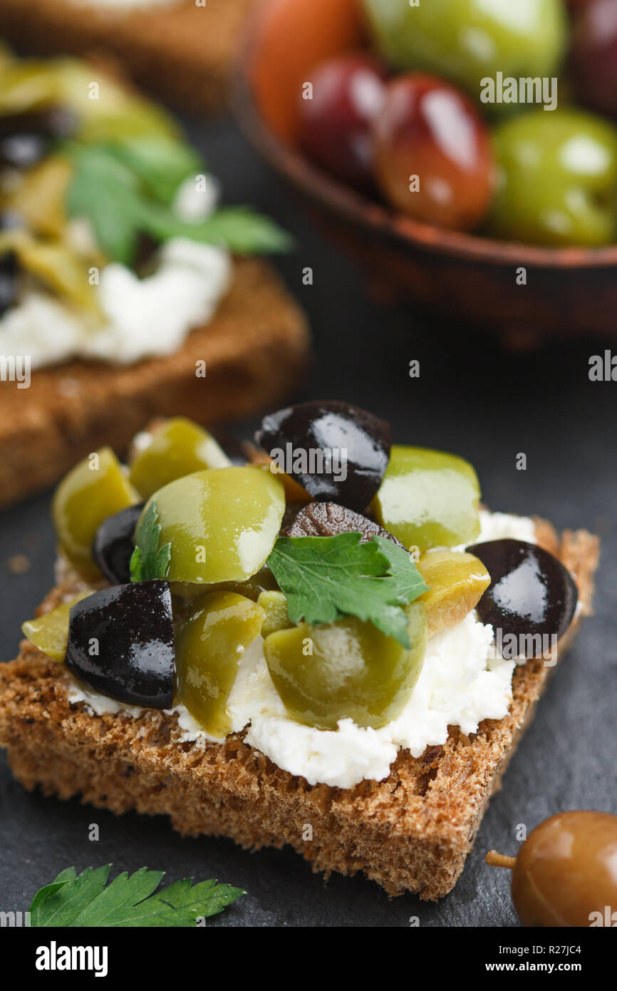 Rye bread toast (canape) with black and green olives, feta cheese and ...
