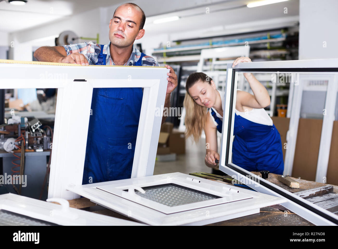 Experienced worker helping girl in work of assembling plastic windows ...