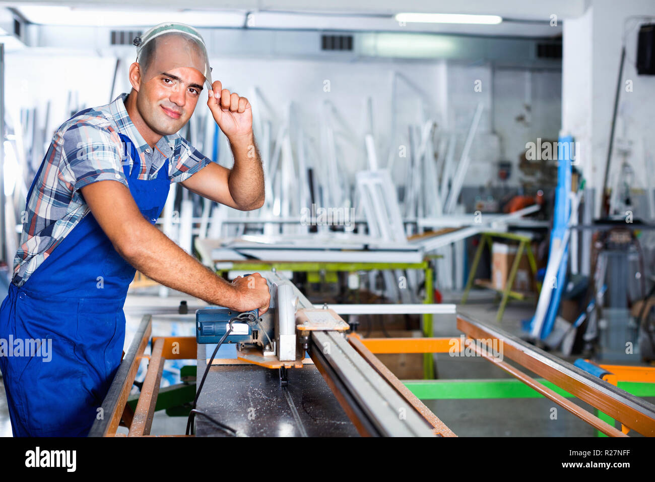 Confident friendly smiling workman ready to working on circular saw in ...
