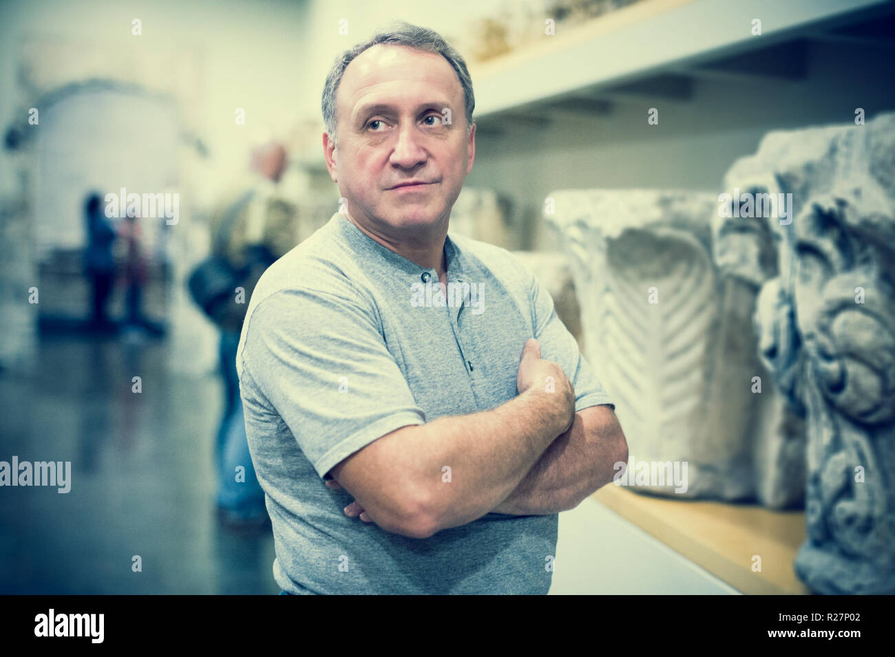 Adult positive man is visiting museum and looking at the exposition ...