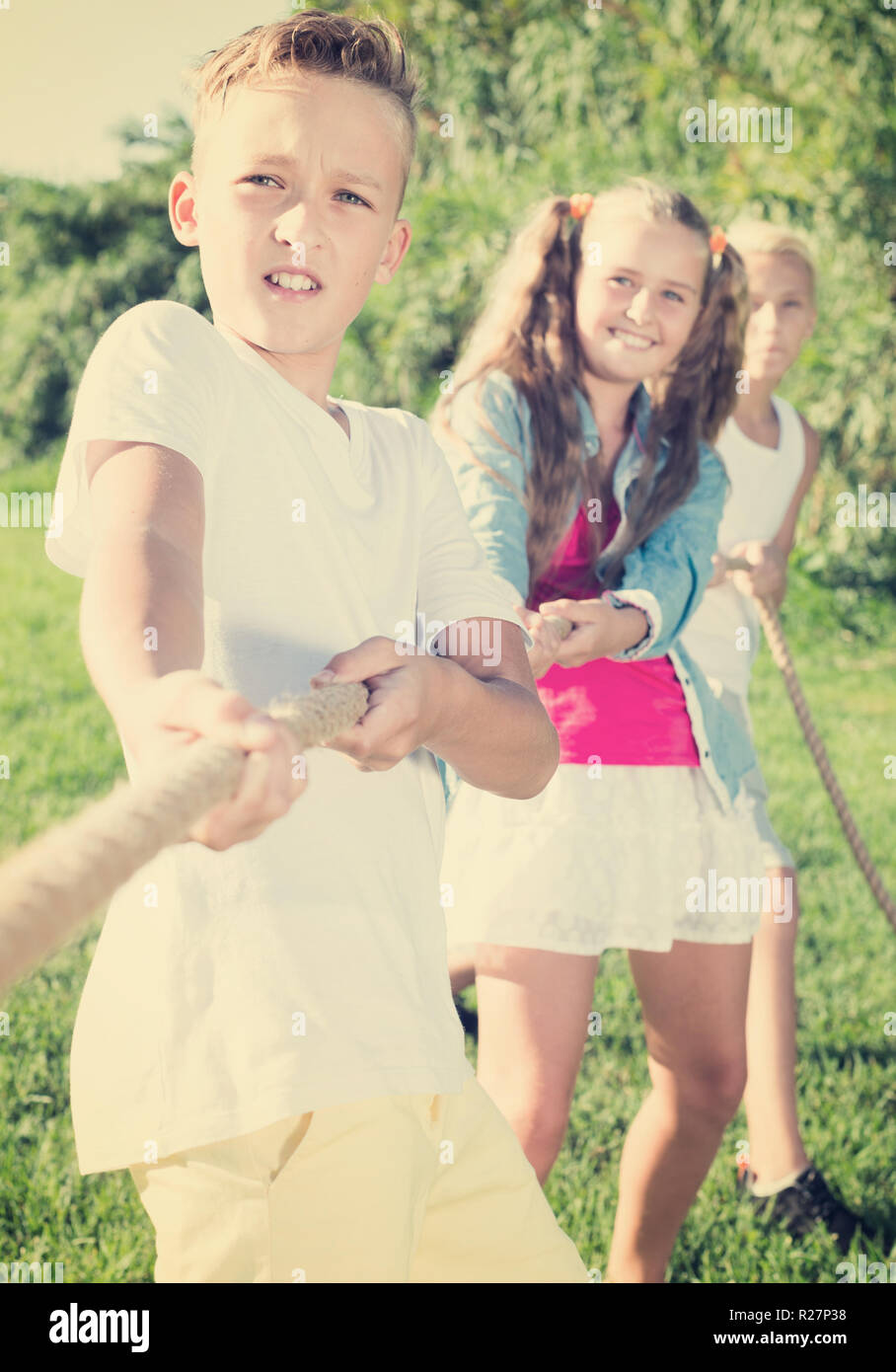 Children playing tug of war during joint games outdoors on sunny day ...
