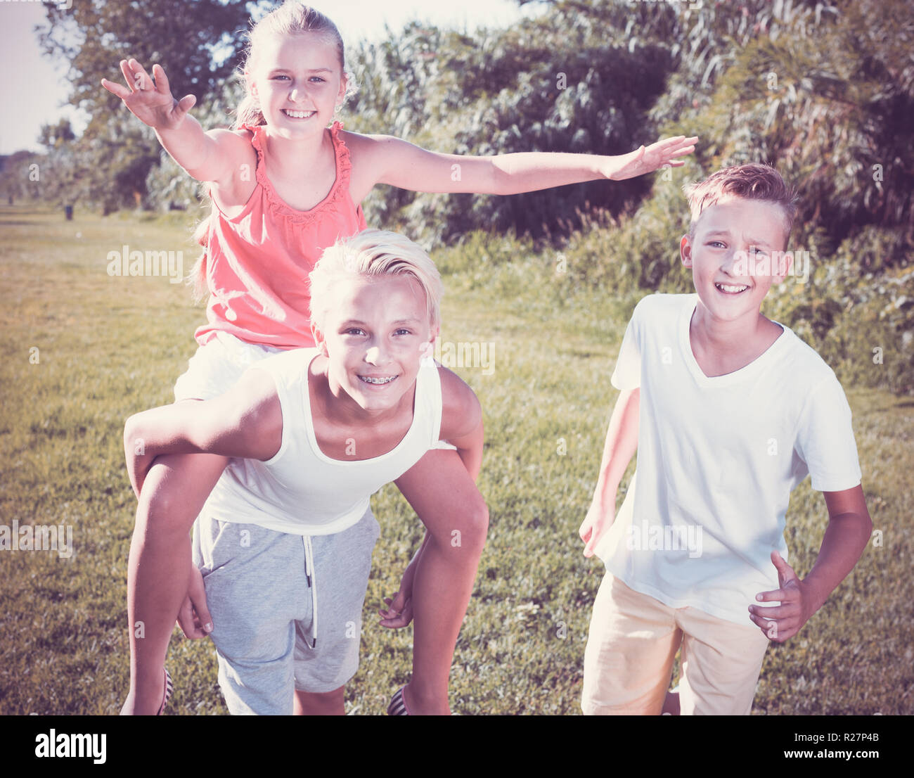 Happy children running together outdoors, boy carrying girl on back ...
