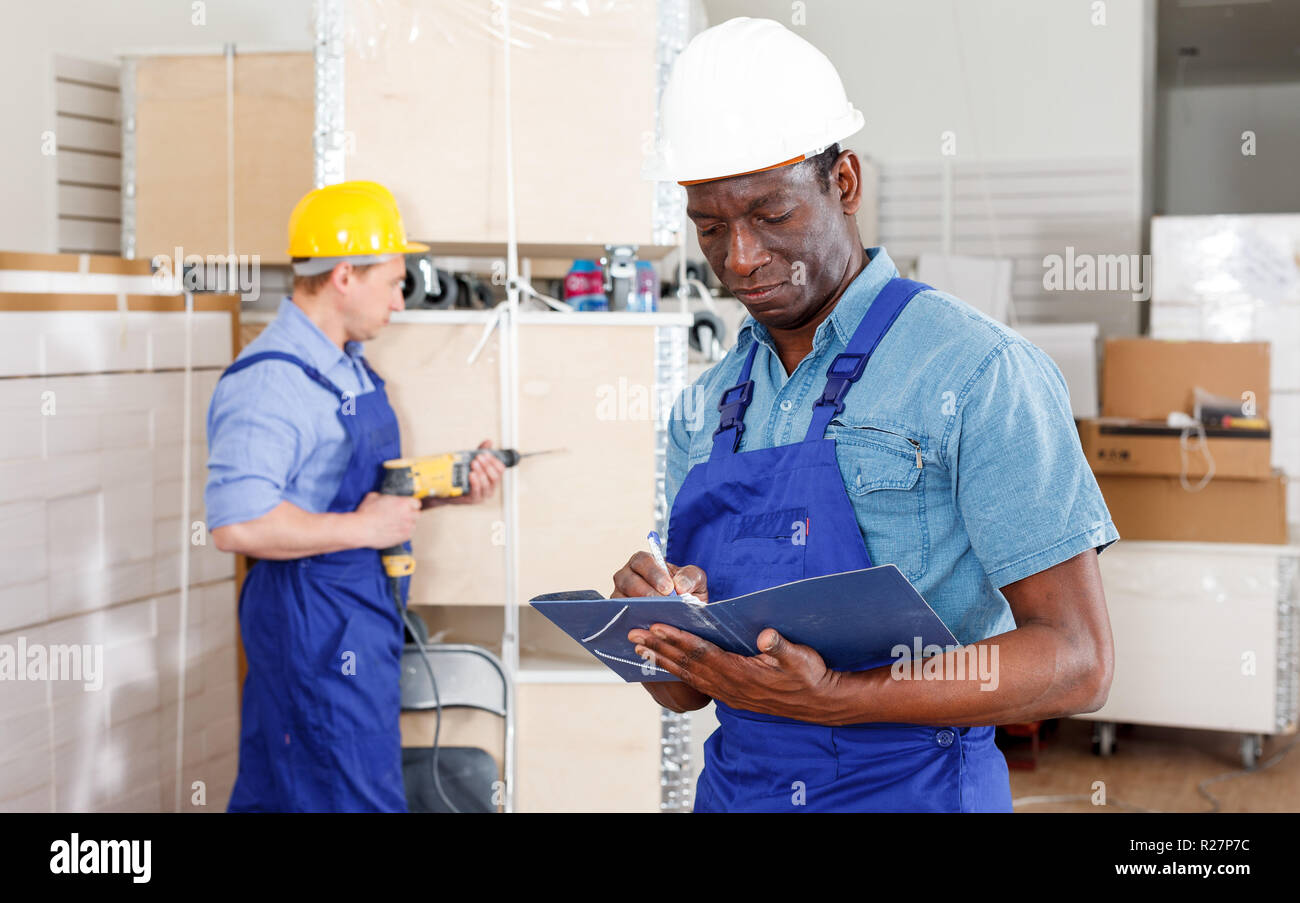 Confident African-American builder examining room and planning ...
