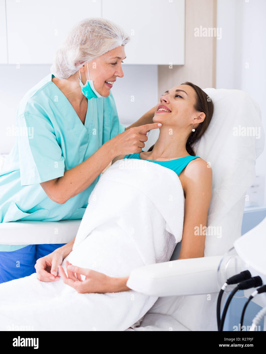 Professional cosmetician explaining future treatment to female patient ...