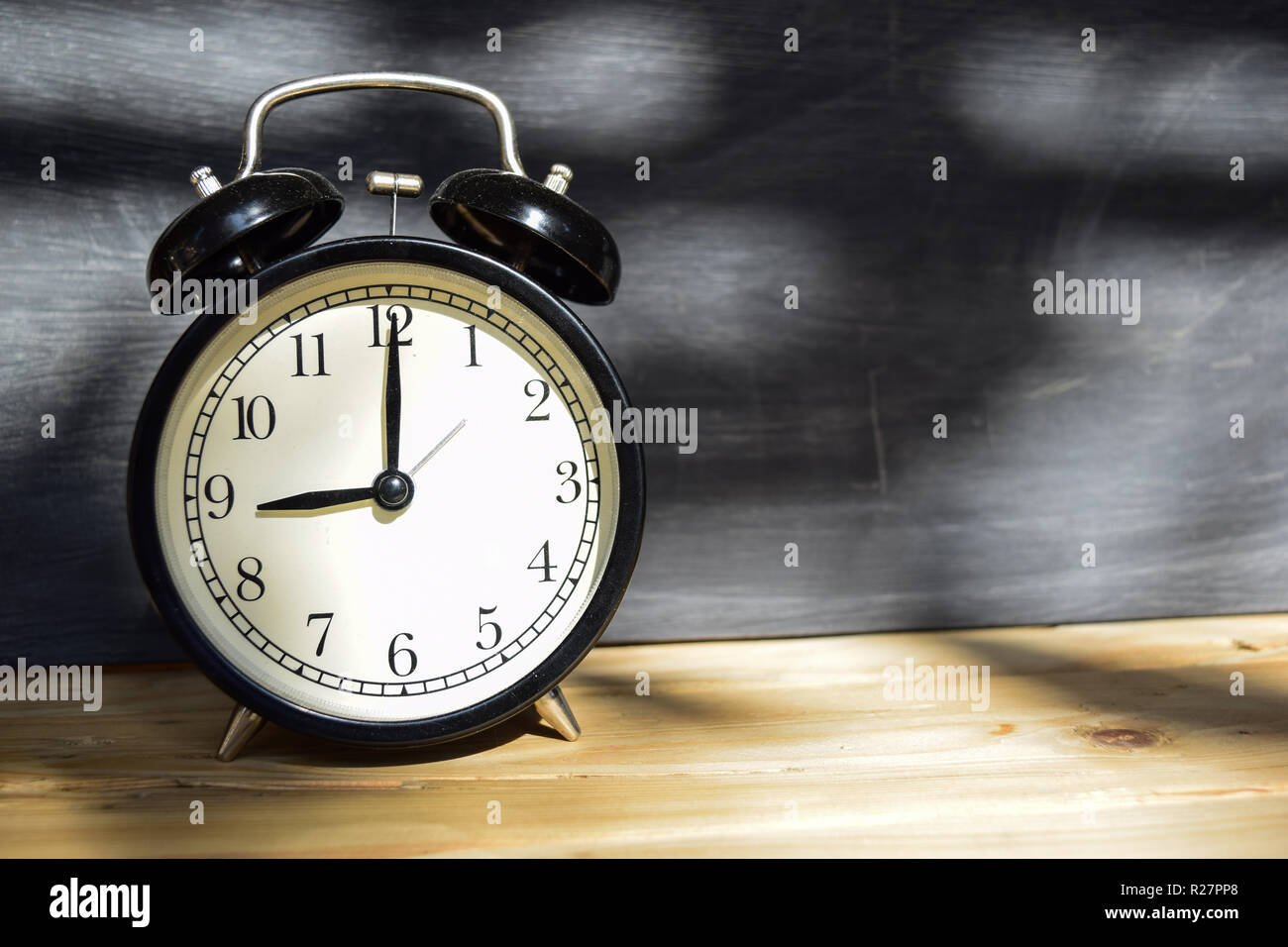 9 am/pm Back to school concept. Alarm clock on wooden with blackboard ...