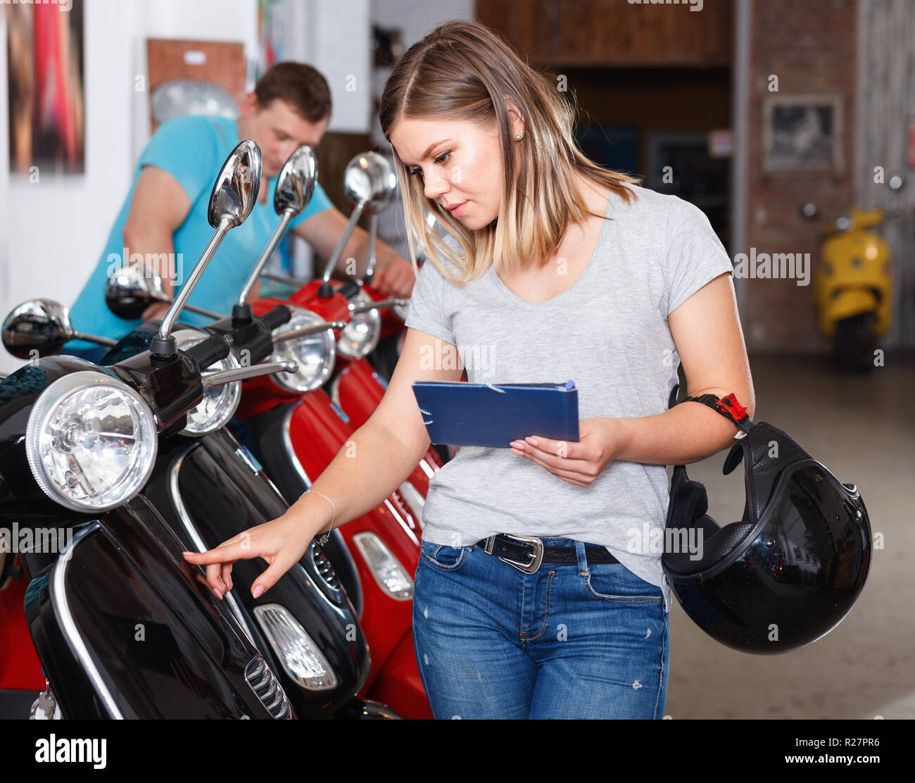 Cheerful positive glad female is shopping and choosing new motobike in ...