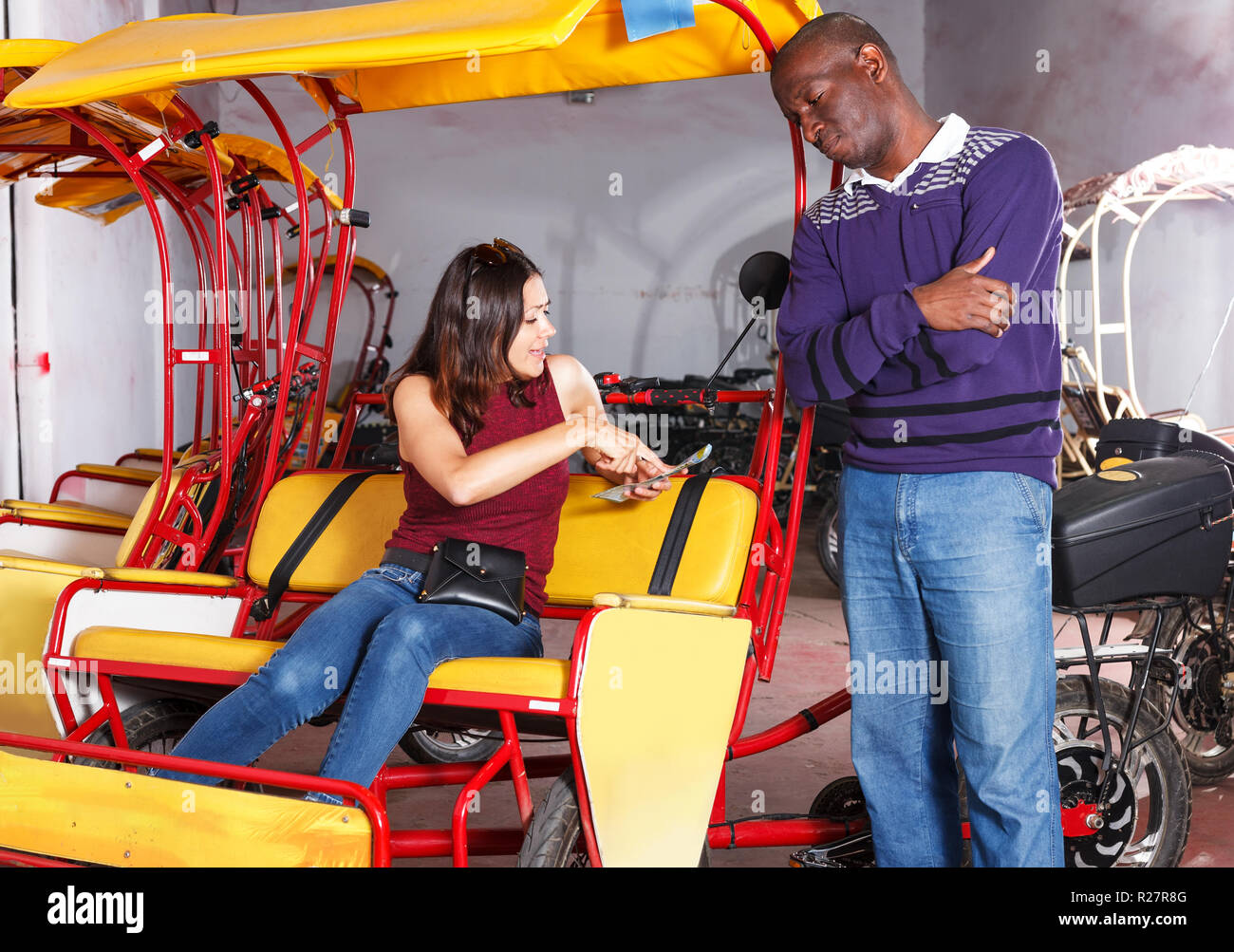 Young woman expressing dissatisfaction with rickshaw service to driver ...