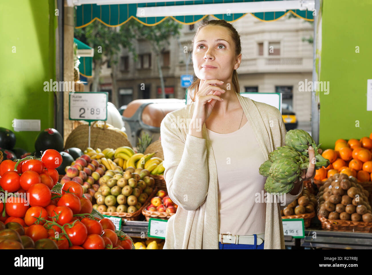 Female is holsing artichokes in the fresh market Stock Photo - Alamy