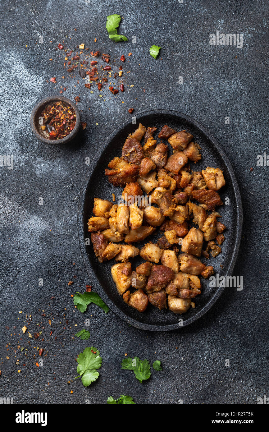 COLOMBIAN CHICHARRON. Fried pork chicharron on black plate. Top view ...