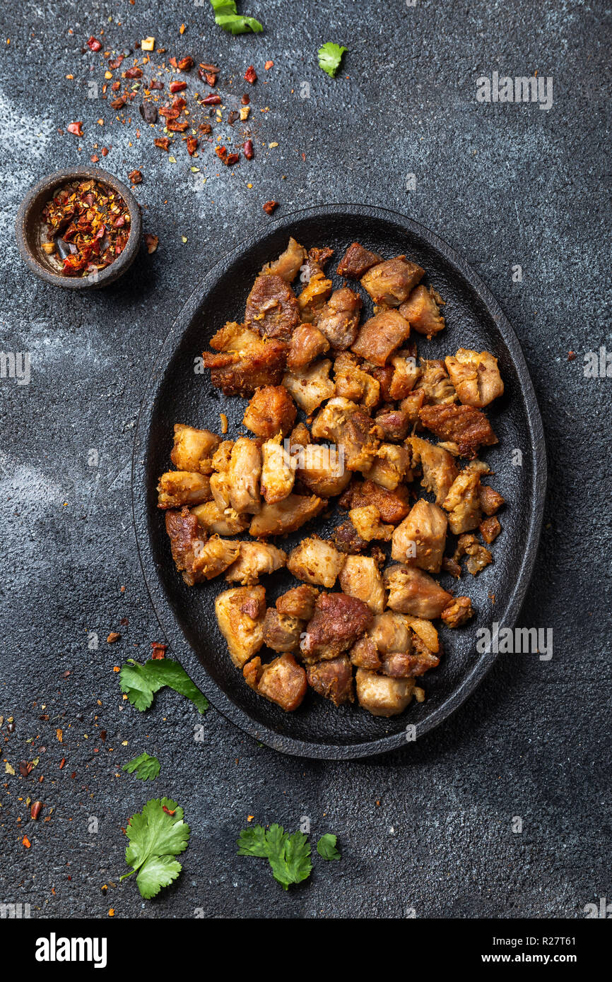 COLOMBIAN CHICHARRON. Fried pork chicharron on black plate. Top view ...