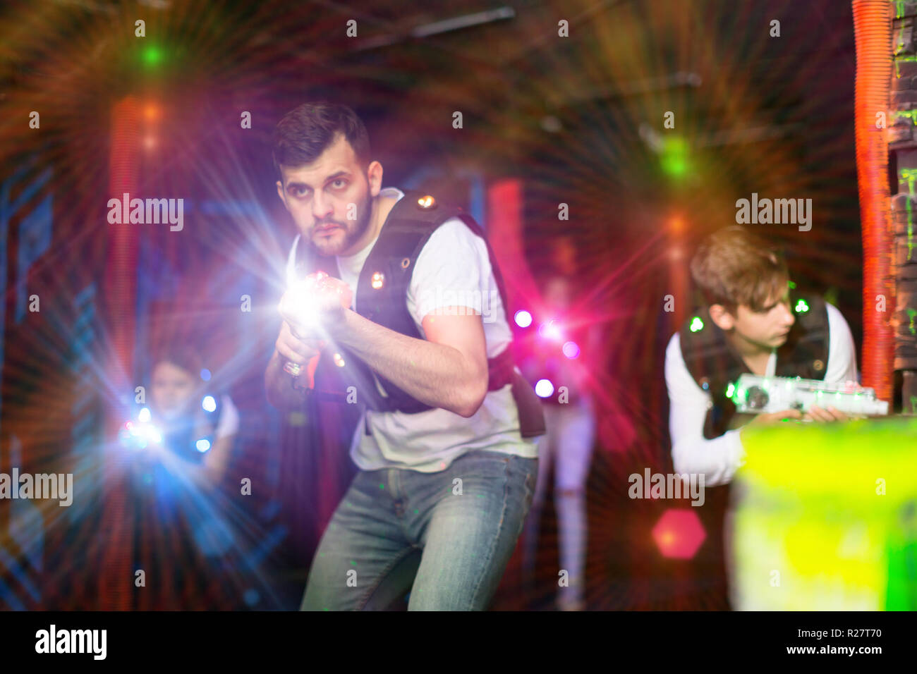 Portrait of excited guy laser tag player with laser pistol in room with ...