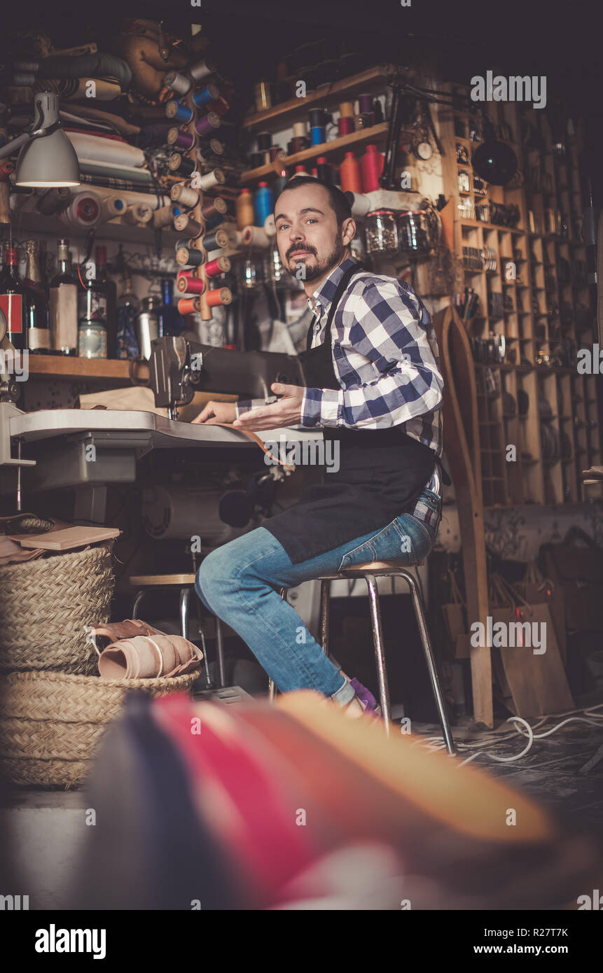 Attractive man worker displaying his workplace and tools in leather ...