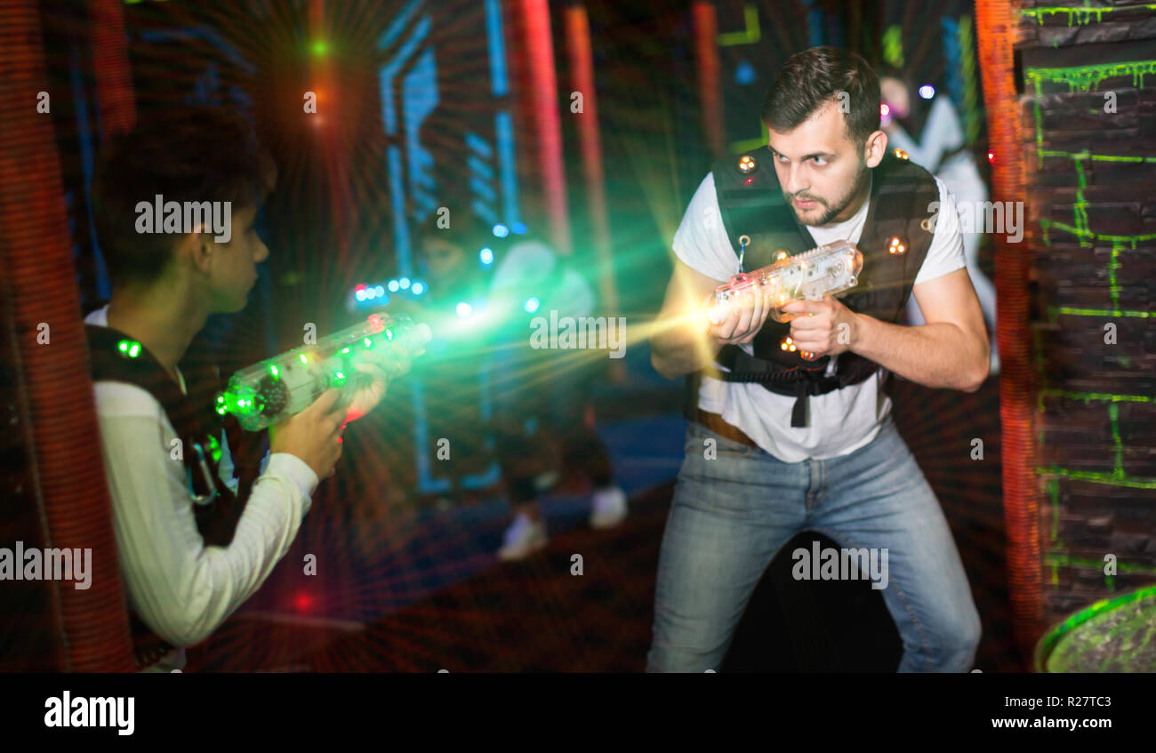 Portrait of guy in colored beams of laser guns during laser tag game on ...