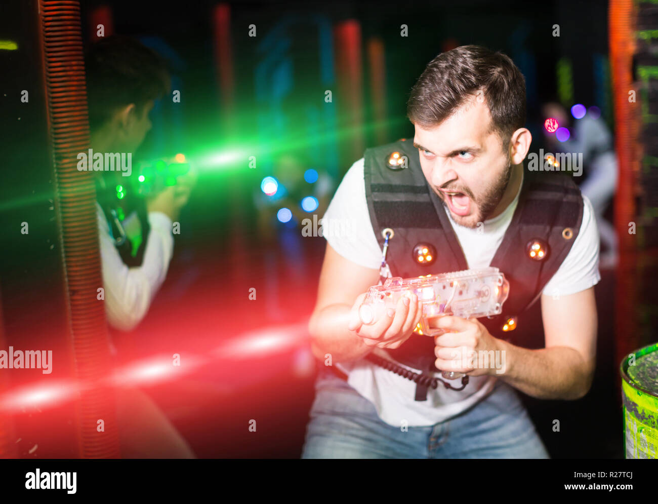 Emotional guy playing laser tag with friends on dark labyrinth in ...