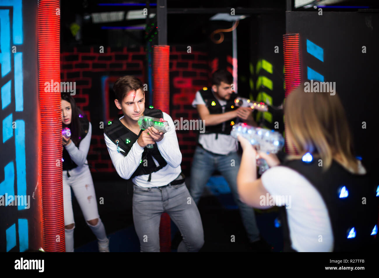 Emotional guy with laser pistol playing laser tag with friends on dark ...