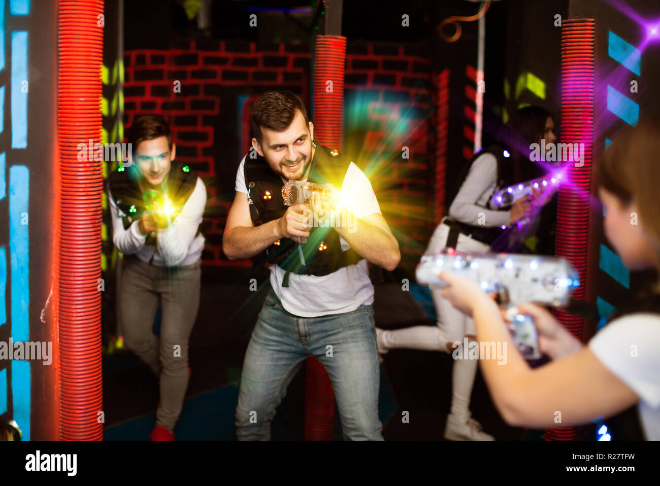 Portrait of guy in colored beams of laser guns during laser tag game on ...