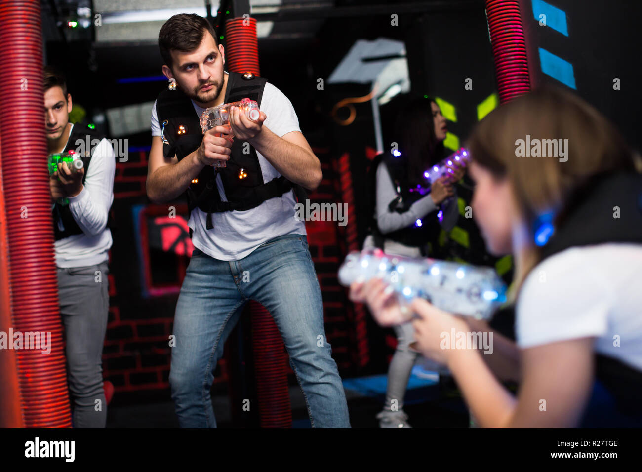 Portrait of young man with laser gun having fun on dark laser tag arena ...