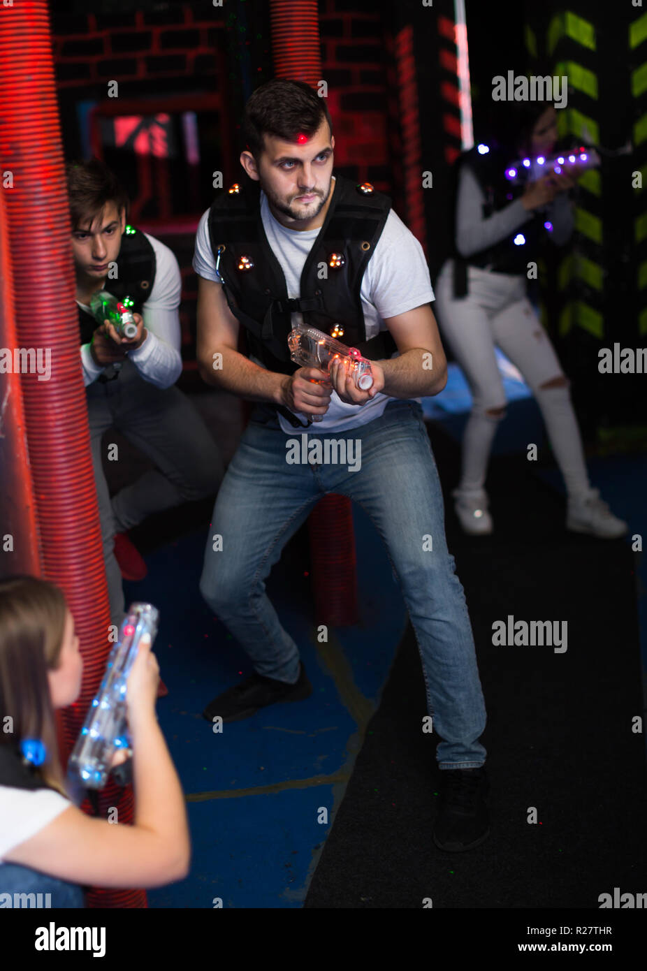 Emotional guy with laser pistol playing laser tag with friends on dark ...