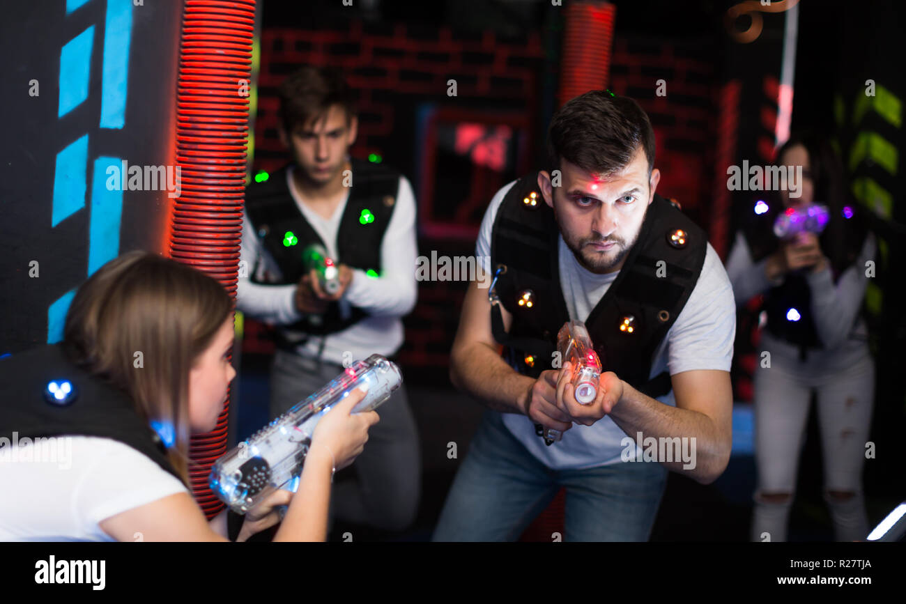 Excited guy aiming laser gun at other players during lasertag game in ...
