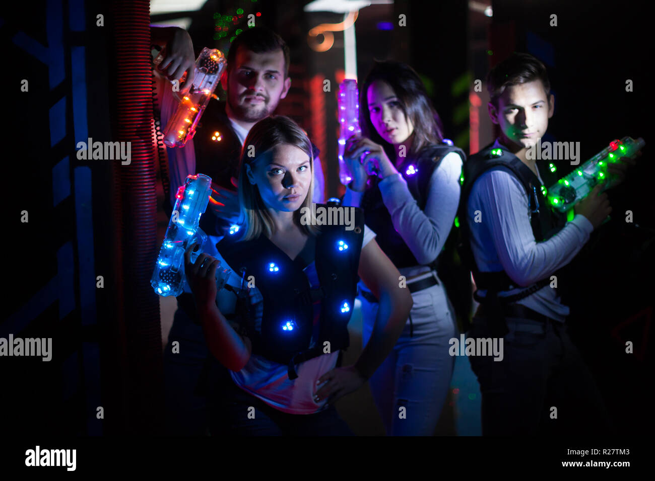 Happy young people with laser pistols posing together on dark laser tag ...