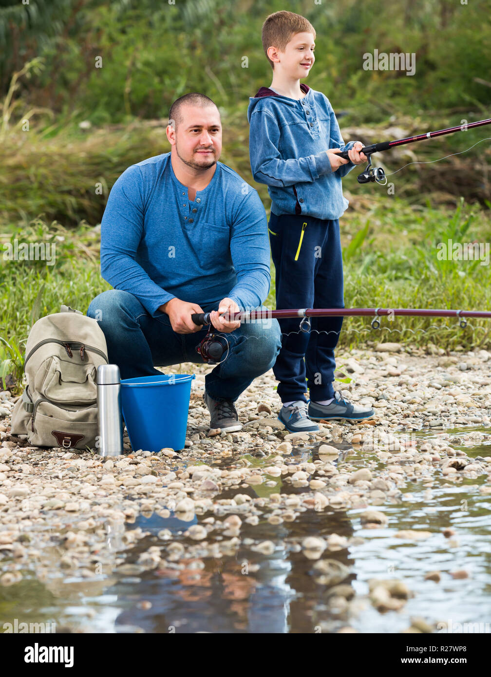 Smiling father and boy fishing with rods in summer day Stock Photo - Alamy