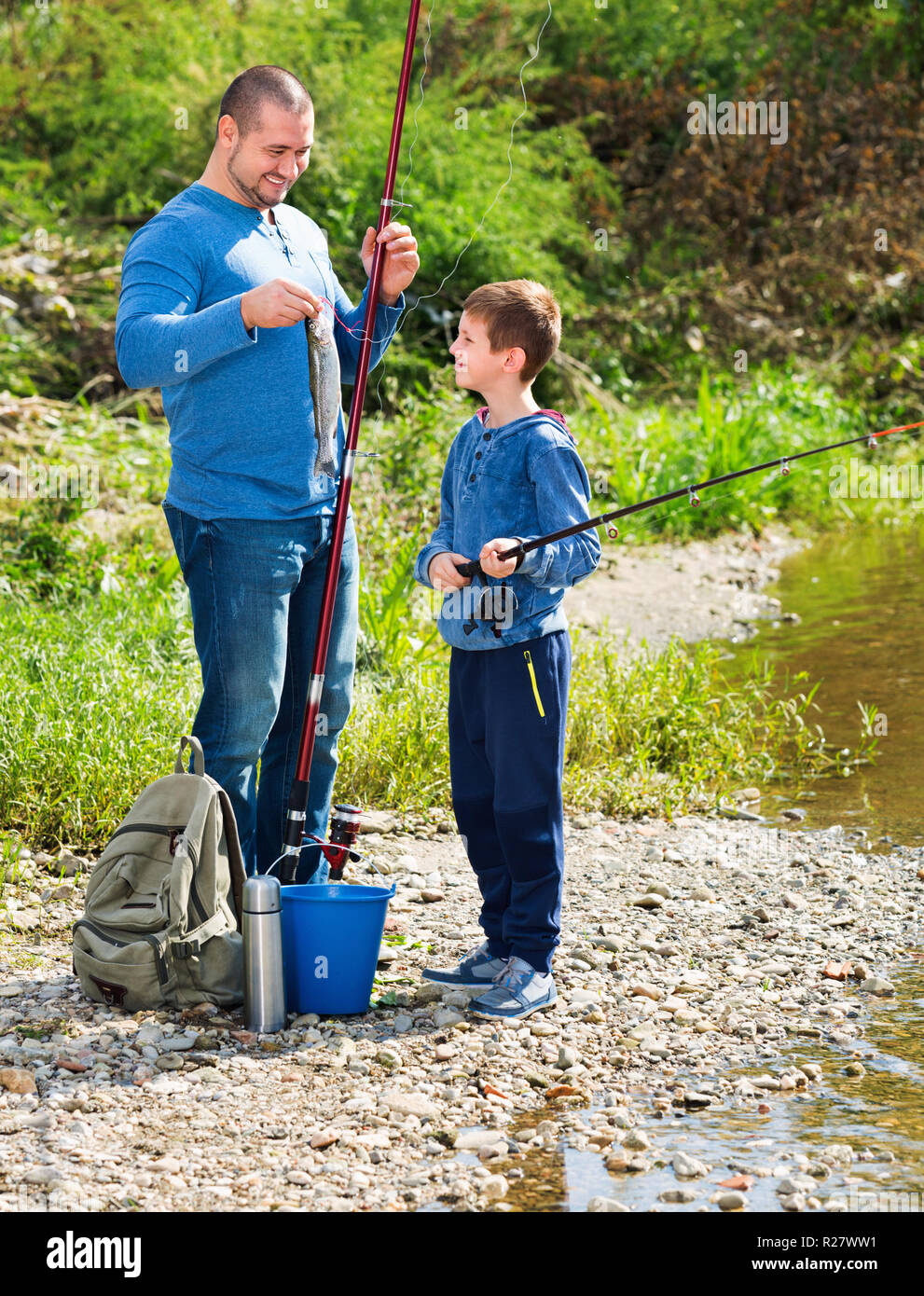 Portrait of happy friendly glad smiling father and cute son fishing ...
