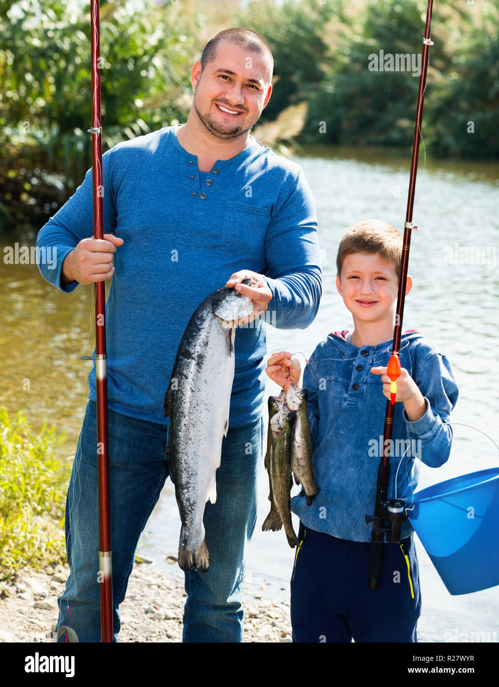 Portrait of friendly father and son fishing with rods in summer day ...