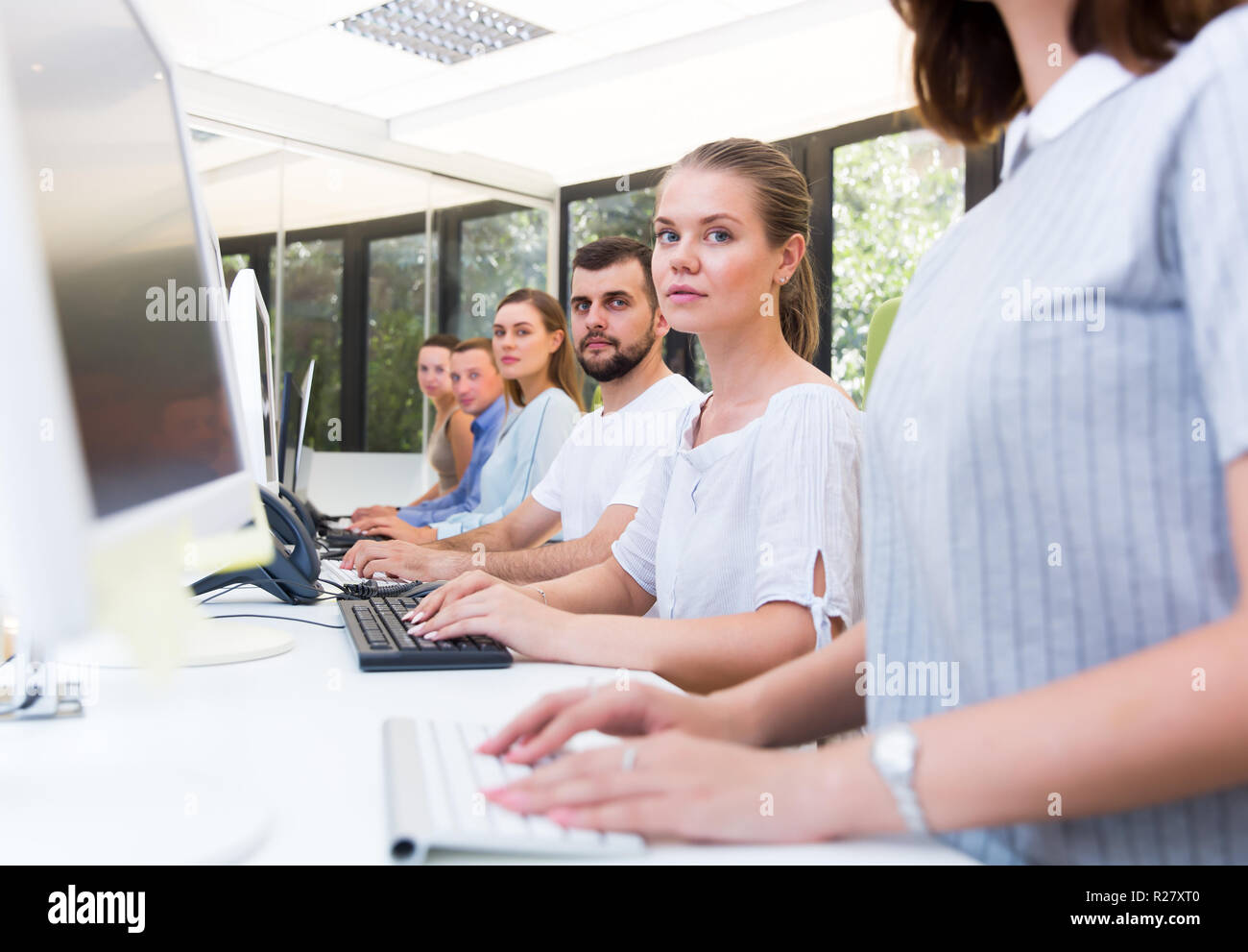 Side view of row of confident business people working with computers in ...