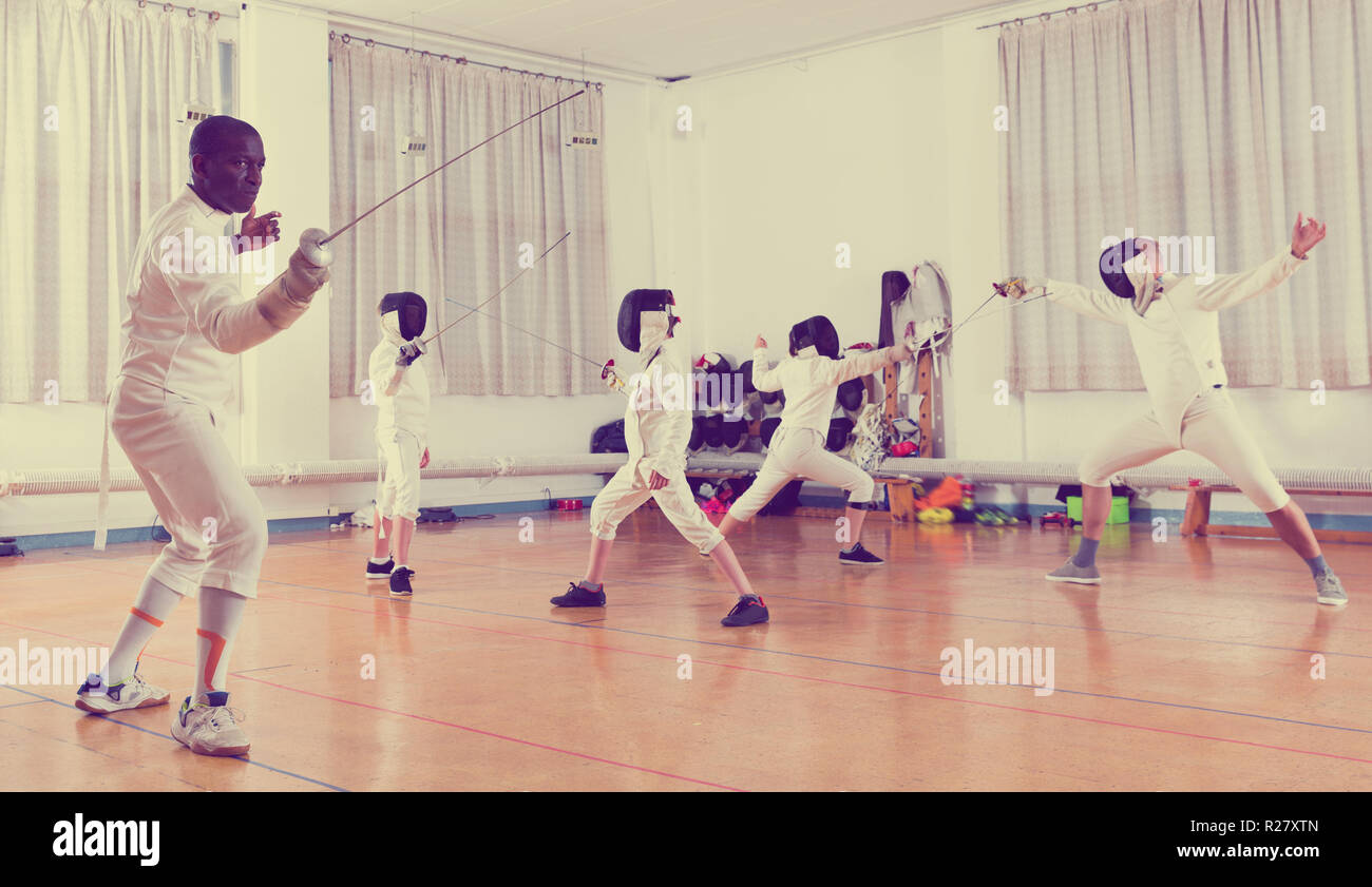 Diligent cheerful smiling coaches demonstrating to young athletes ...