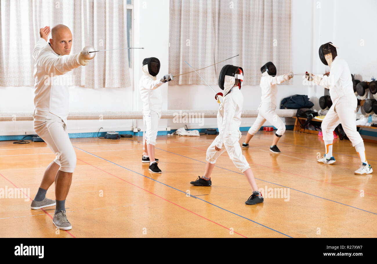 Positive cheerful smiling coaches demonstrating to young athletes ...