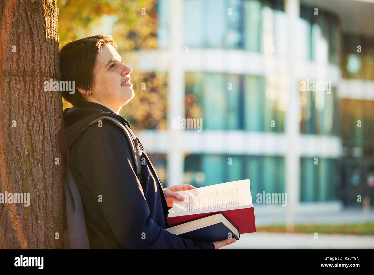 Woman leaning against a tree and reading a book hi-res stock ...