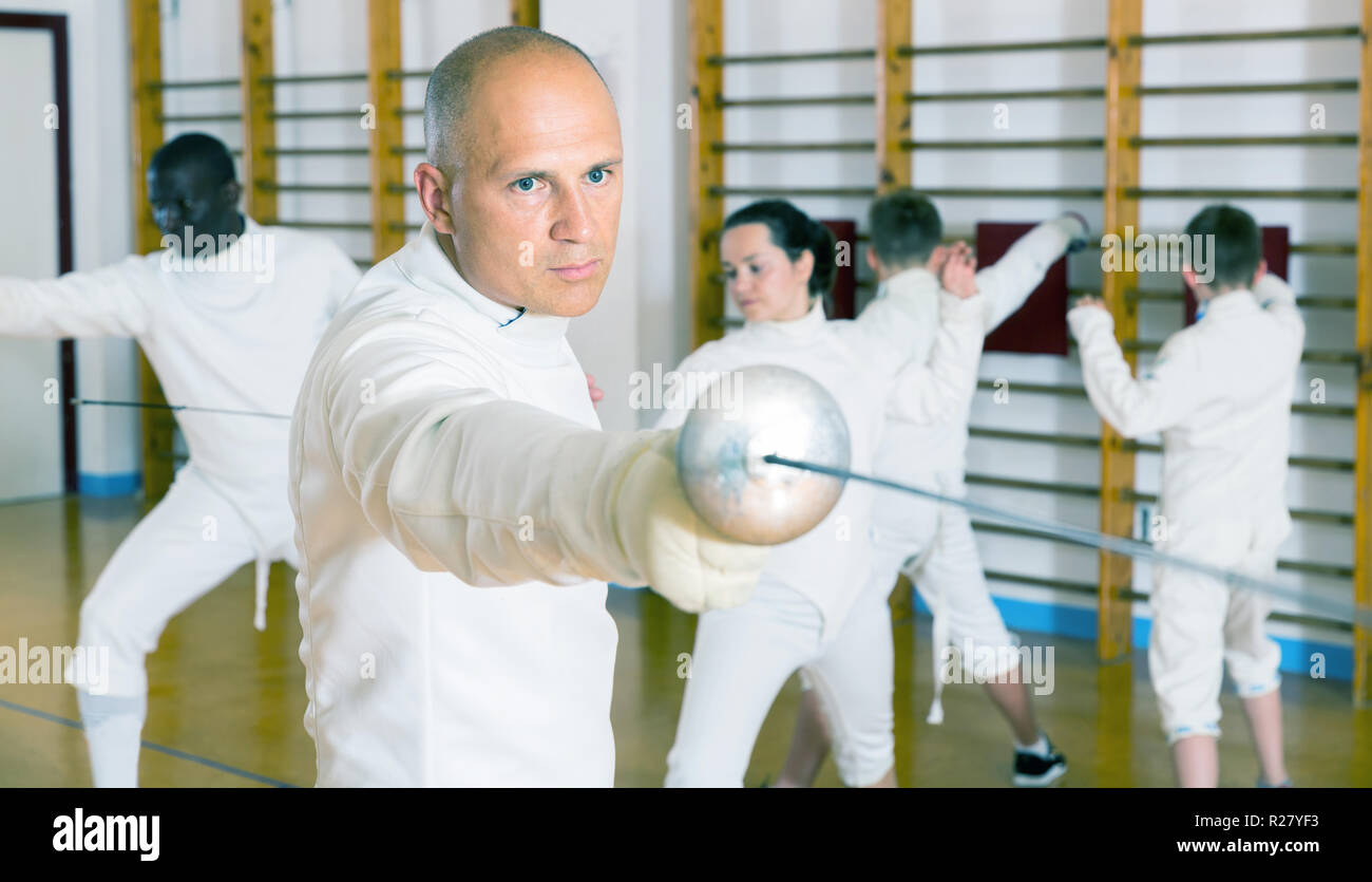 Man athlete training attack movements with rapier at fencing workout in ...