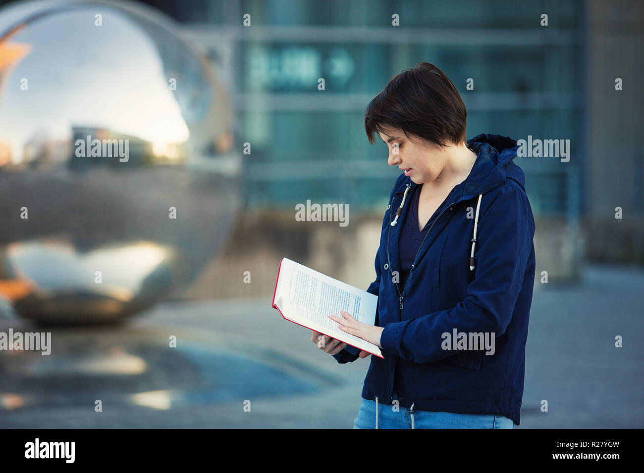 Young woman student outdoors urban street portrait reading a book ...