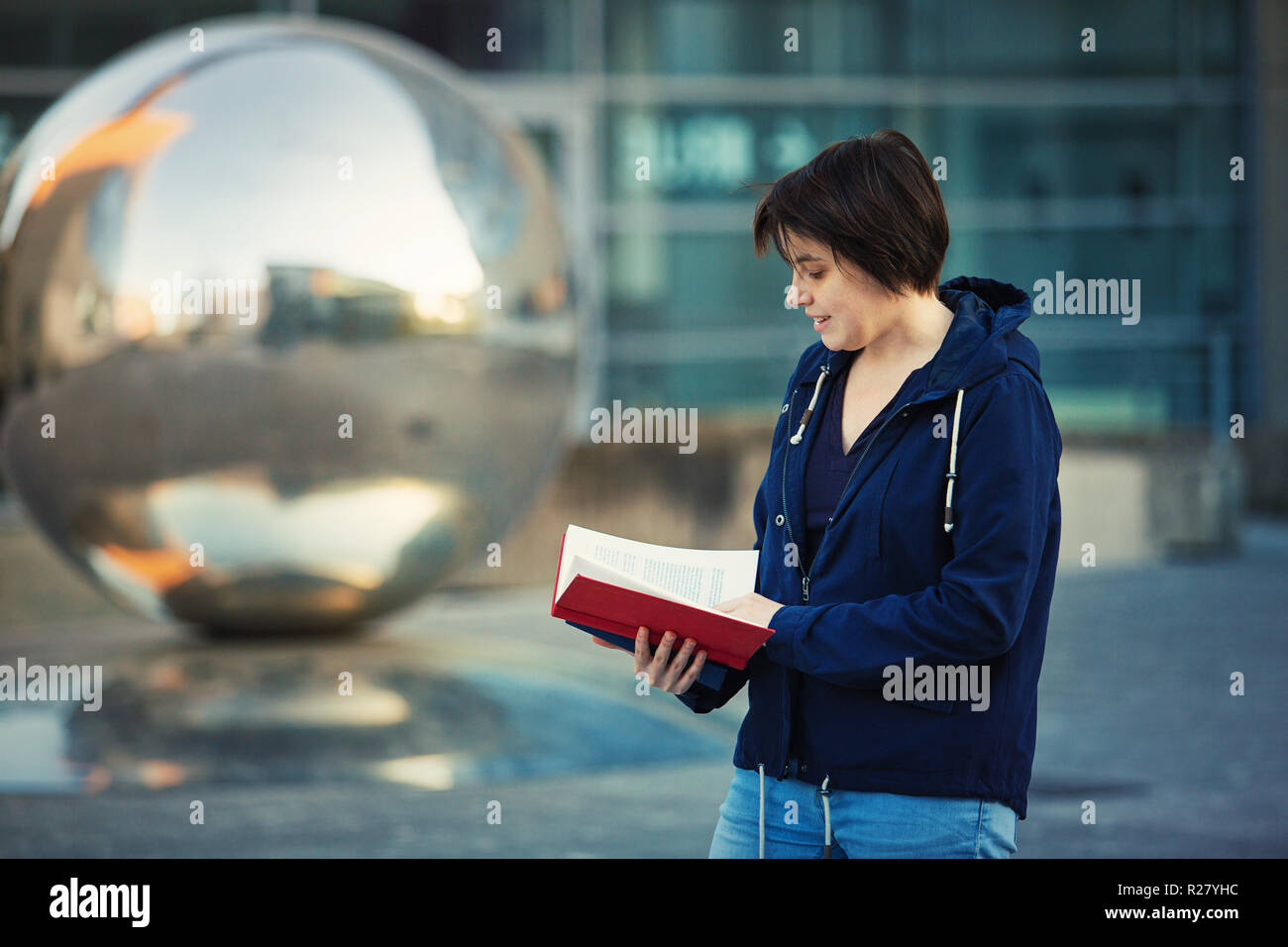 Young woman student outdoors urban street portrait reading a book ...