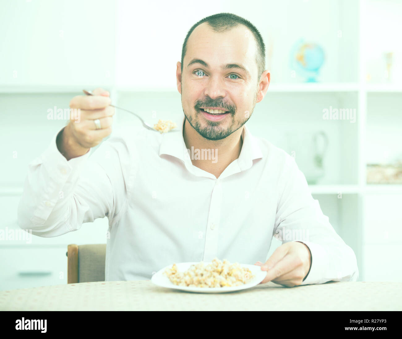 Positive young man ready to eat oat porridge in office Stock Photo - Alamy