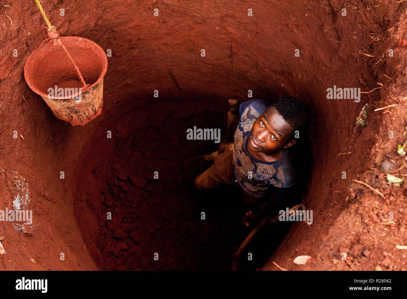 young african boy inside water well in africa during digging looking in ...