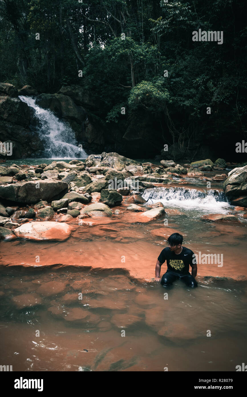 Man resting on rock at a waterfall in the rainforest of Malaysia Stock ...