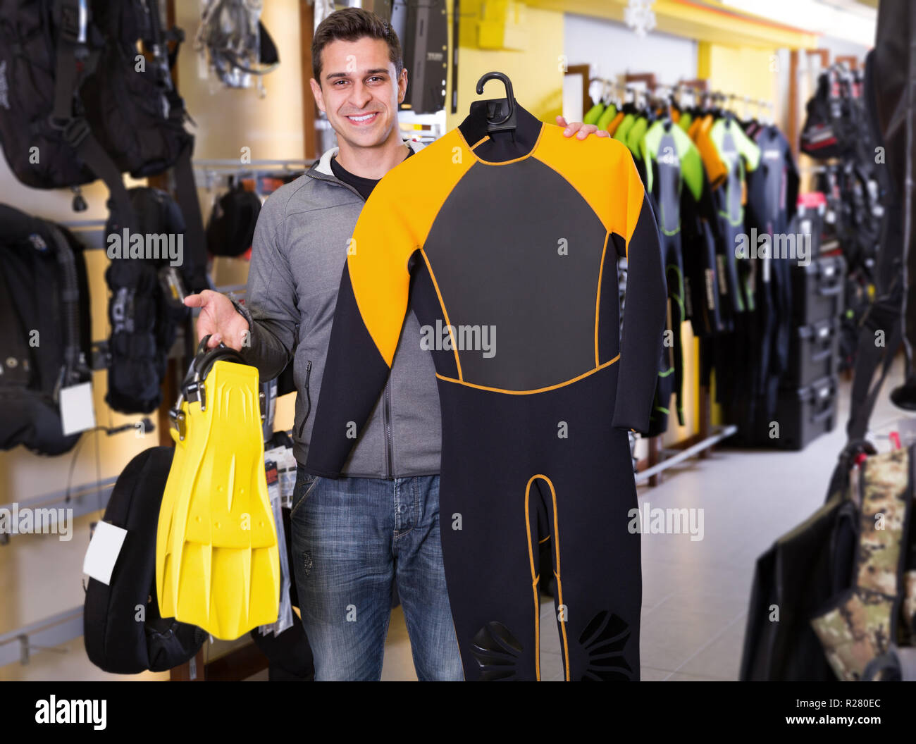 Smiling man standing with sport diving costumes and flippers in the ...