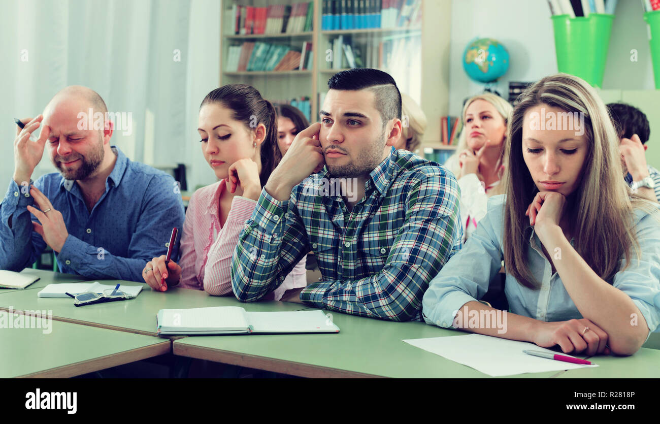Portrait of bored adult students sitting at lesson in classroom Stock ...