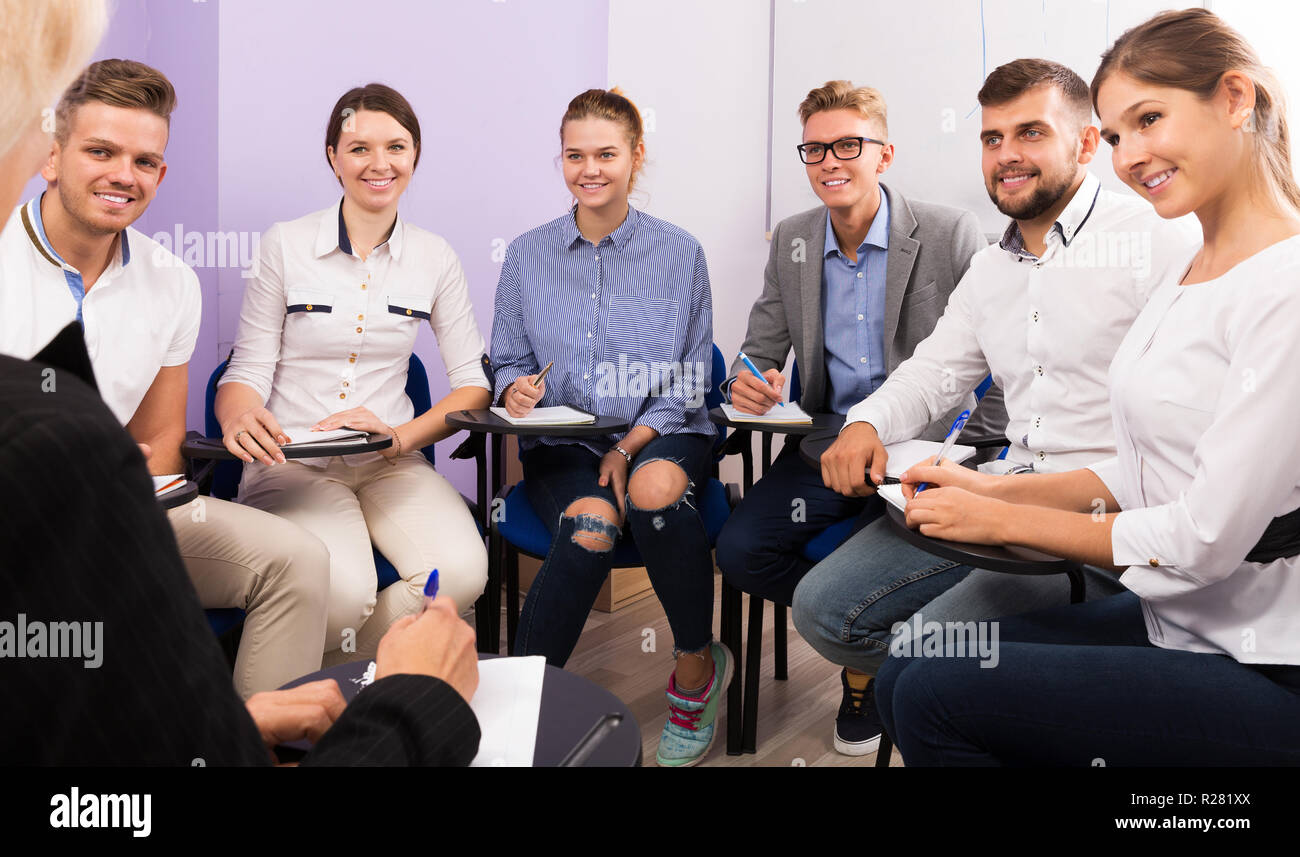 Portrait of smiling adult group of students listening teacher in ...