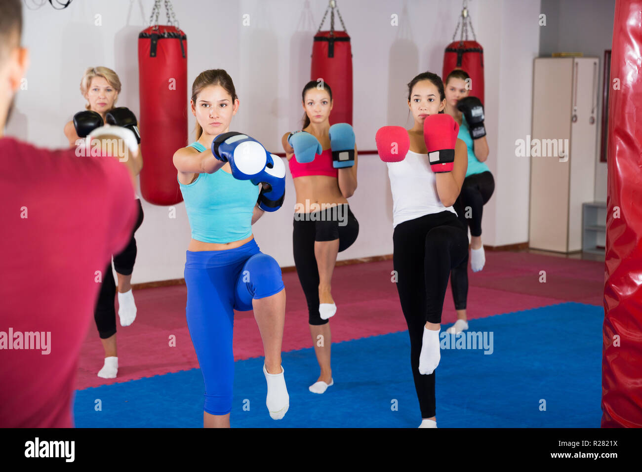 Sporty adult women are boxing and doing kick with coach in sporty gym ...